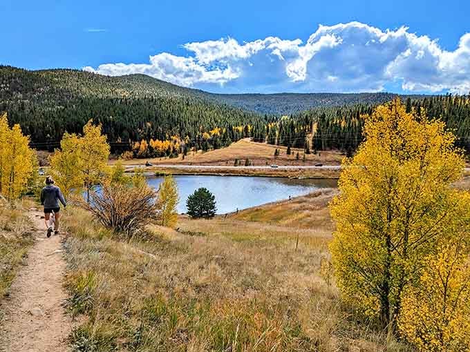 Fall colors explode around the peaceful lake while a lone hiker enjoys nature's spectacular show in blessed solitude.
