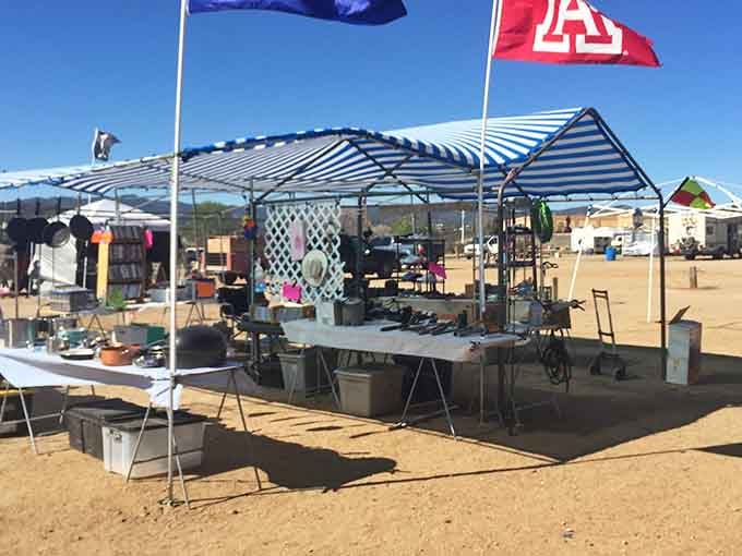 Striped canopies and waving flags mark vendor territories in this friendly outdoor marketplace under endless blue skies.