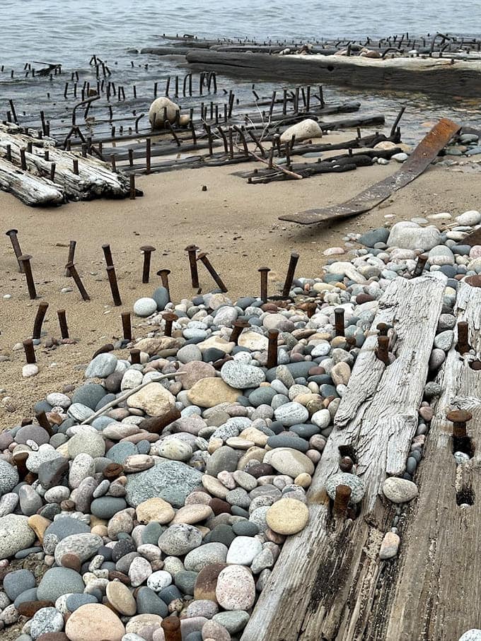 Shipwreck remnants scattered on the beach serve as haunting reminders of why this lighthouse was so desperately needed.