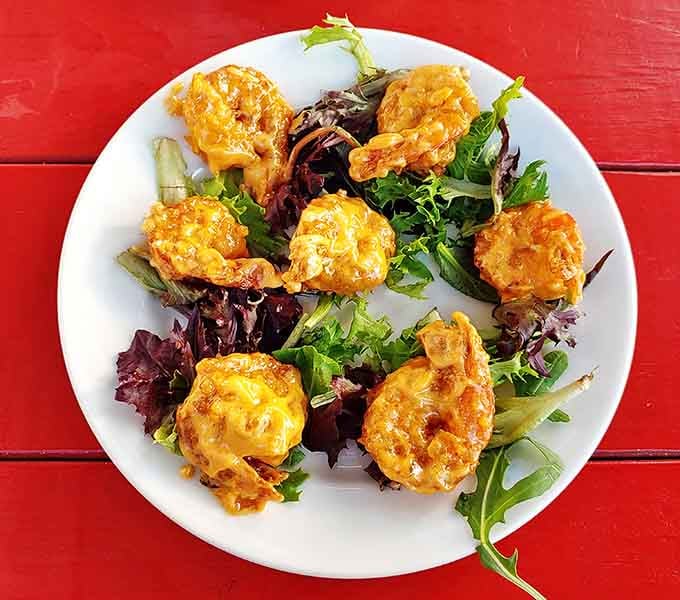These crispy shrimp bites perched on fresh greens deliver a perfect balance of crunch, spice, and oceanic sweetness.