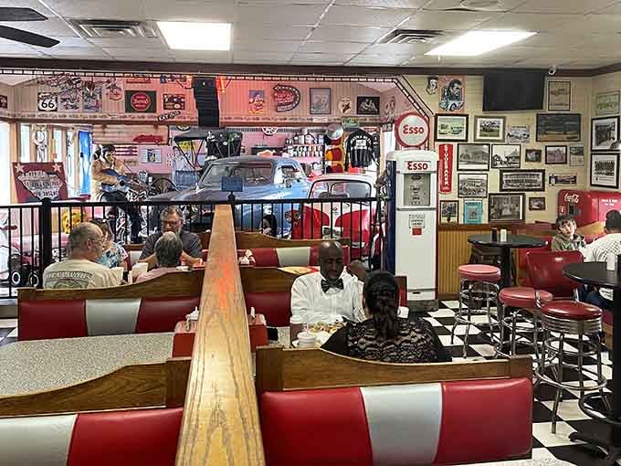 Diners enjoying their meals surrounded by vintage cars and memorabilia, living their best retro life right now.