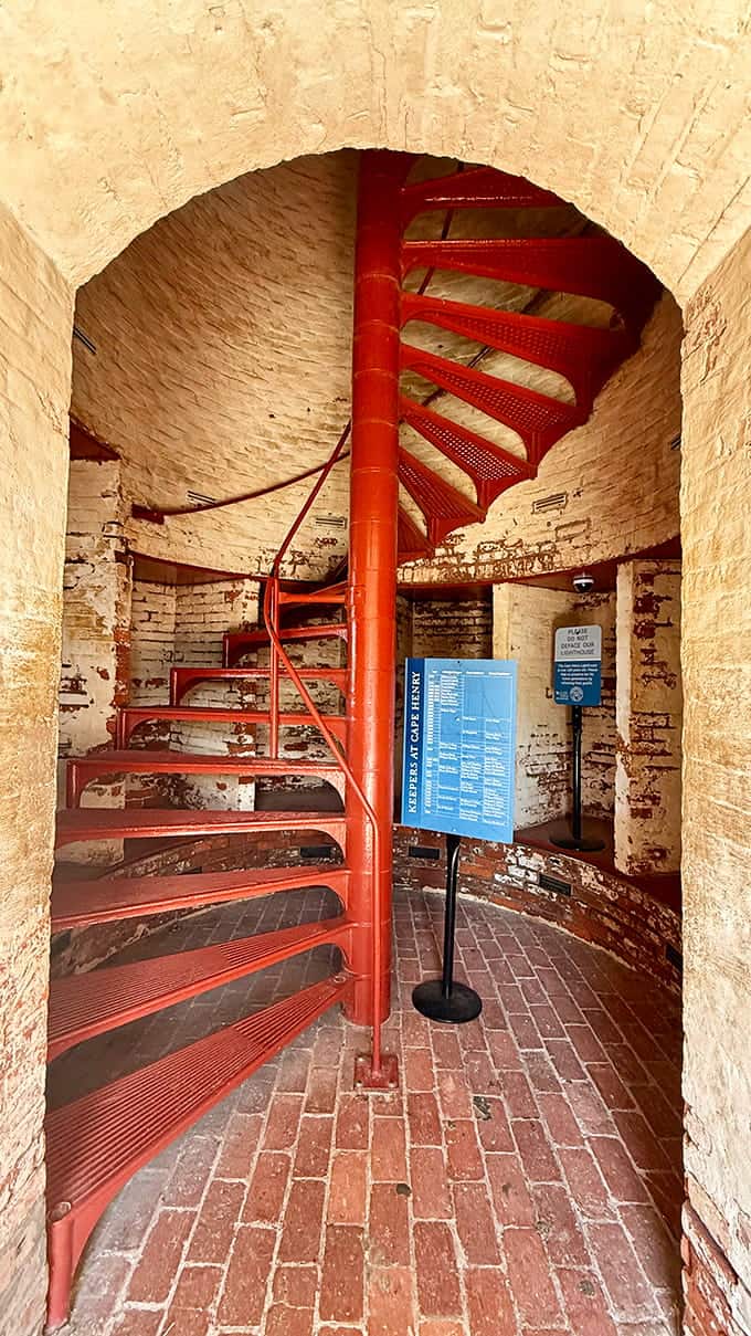 That red spiral staircase is your ticket to the top, winding upward like a corkscrew through centuries of maritime history.
