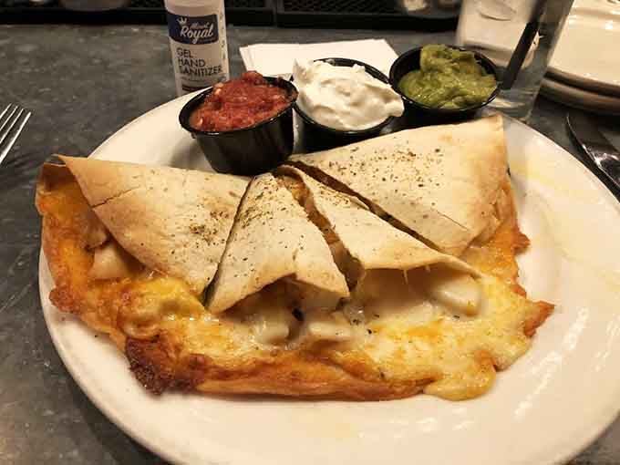 A quesadilla that's achieved the perfect cheese-pull-to-filling ratio, flanked by condiments standing at attention like delicious little soldiers.