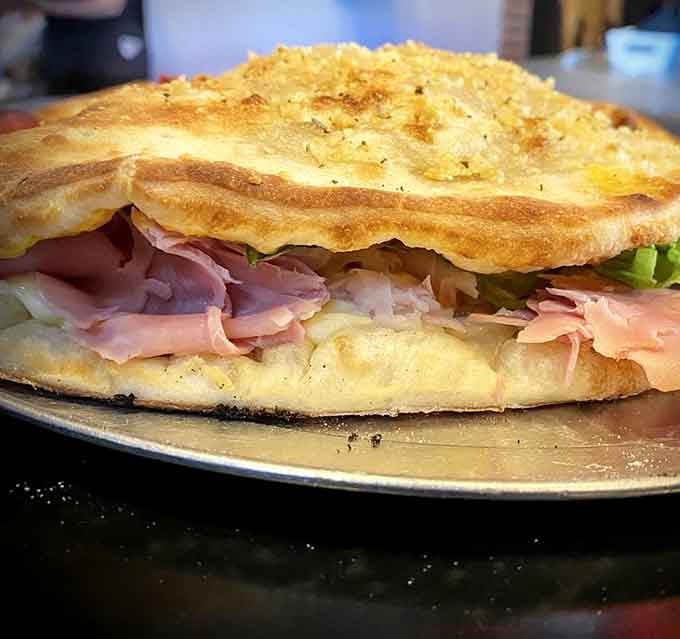 The Triple Club Sandwich stacked between pizza dough proves carbs on carbs is always a good idea.