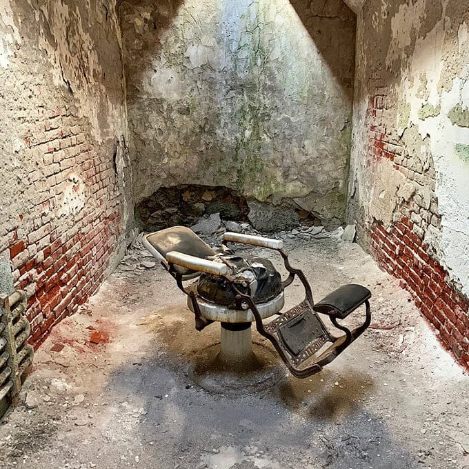 That vintage barber chair sits frozen in time, a mundane object made eerie by its abandoned surroundings.
