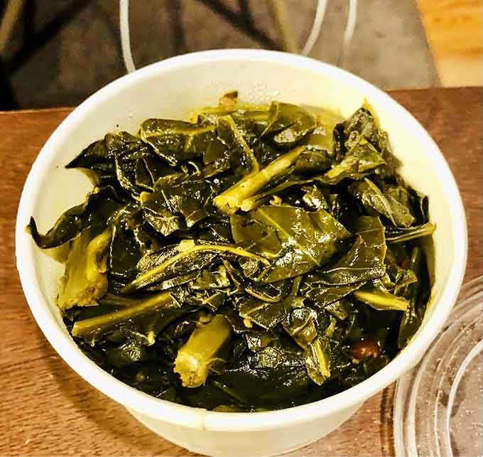 Collard greens cooked down to tender perfection, proving vegetables can absolutely hold their own at a barbecue joint.