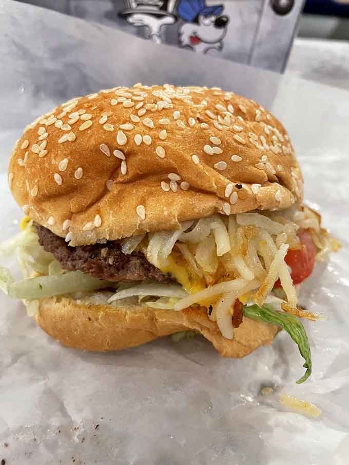 Sesame seed bun crowning a burger that's been customized with all the fixings, delivered fresh from the overhead express line.