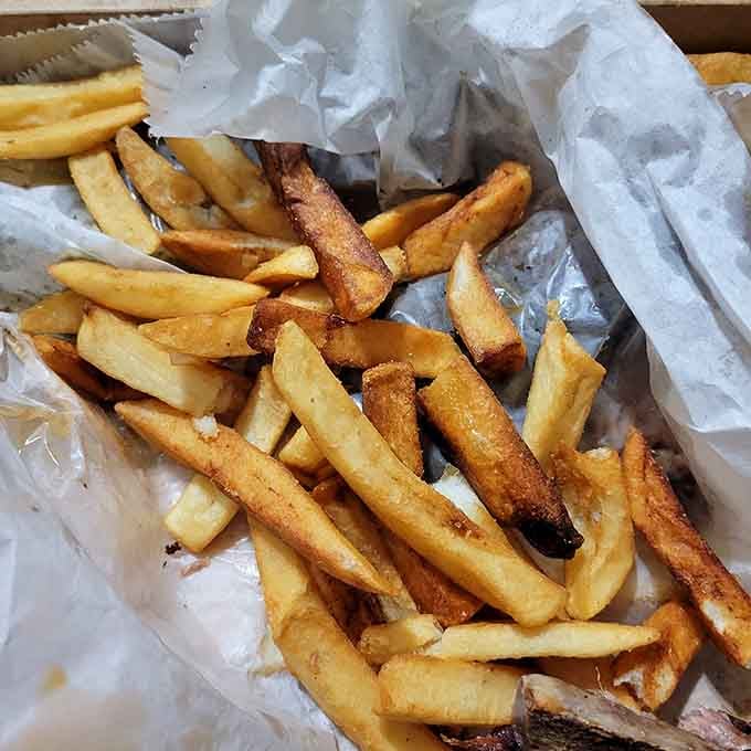 Hot fries tumbling from paper, seasoned and perfect for mopping up every last drop of sauce.