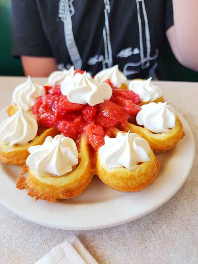 Belgian waffles topped with strawberries and whipped cream, because sometimes you need dessert disguised as breakfast to start right.