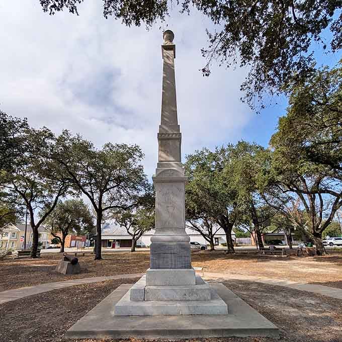 The Fannin Memorial stands as a solemn reminder of sacrifice, surrounded by peaceful trees and thoughtful silence.