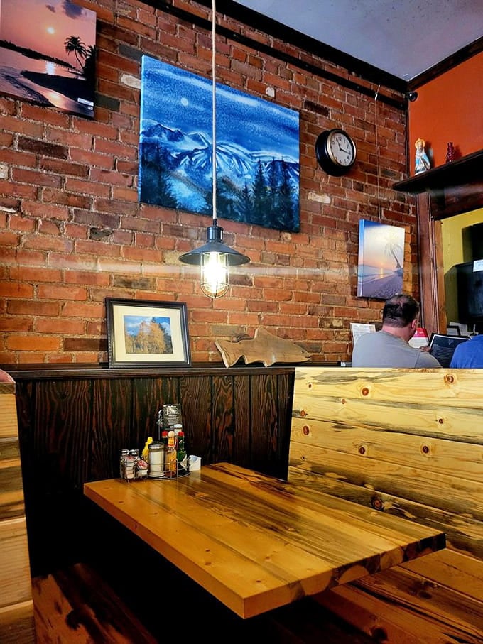 Exposed brick walls and mountain artwork create a dining space that feels authentically Colorado without trying too hard to prove it.