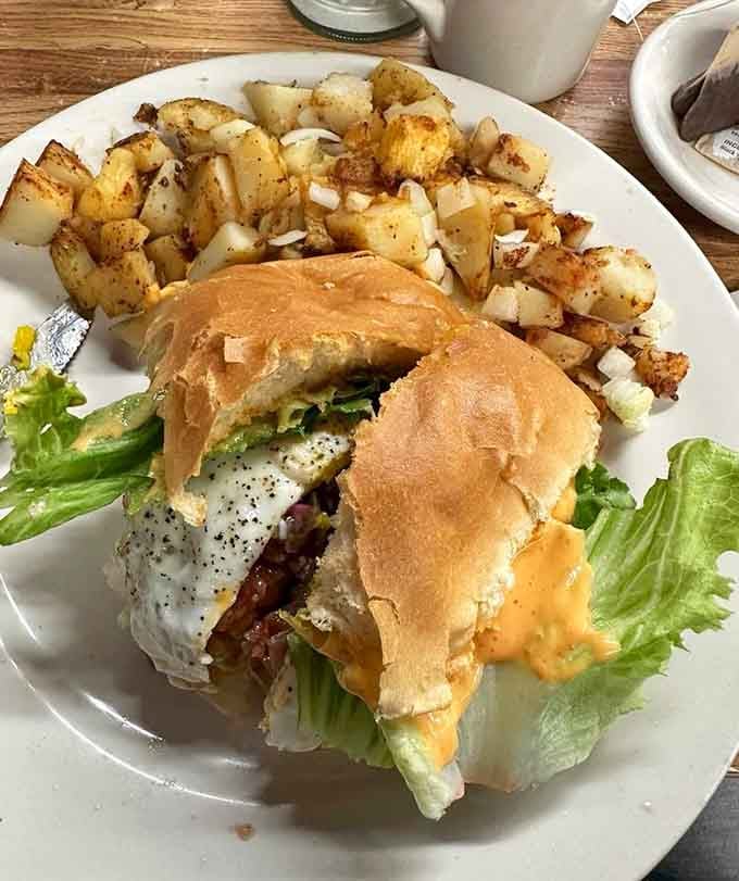 Brunch done right! Crispy home fries and a juicy burger stacked with a perfectly fried egg and melty sauce—comfort food at its finest.