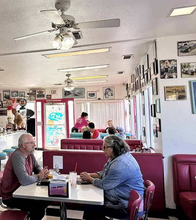 Diners enjoying their meals in booths beneath ceiling fans and vintage photos, living their best 1950s fantasy life.