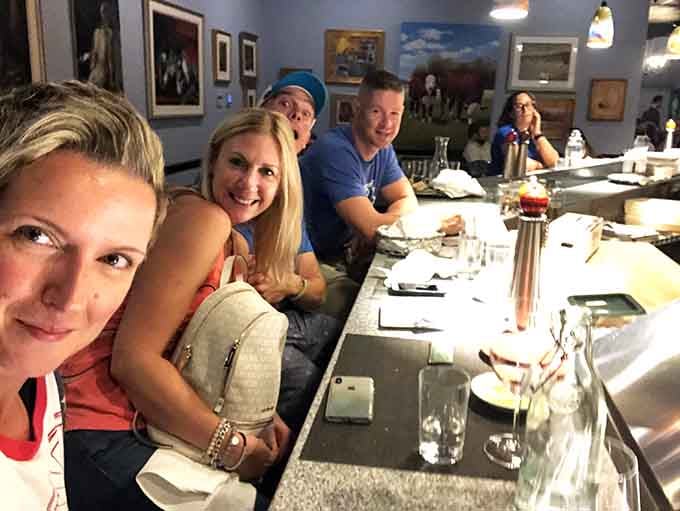 Happy diners gathered at the bar capture the convivial spirit that makes Out of the Fire feel like home.