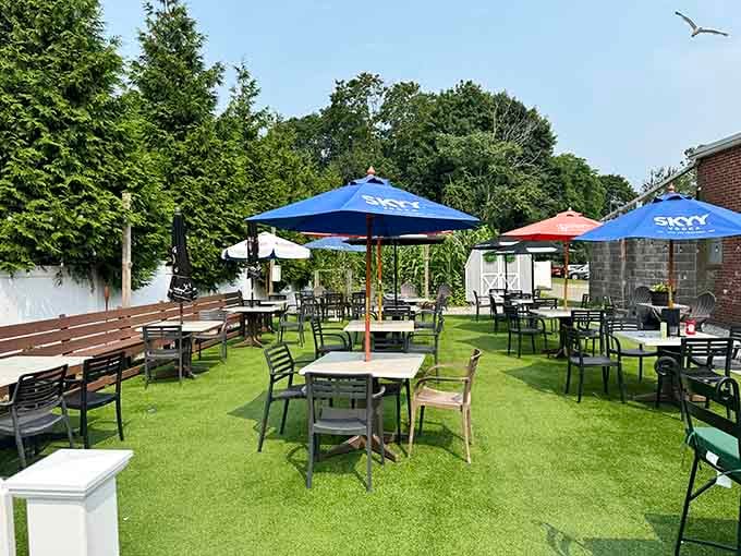 The outdoor patio offers fresh air, green grass, and the perfect setting for enjoying good food under blue skies.