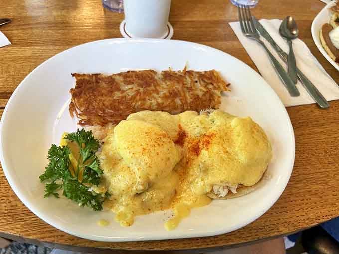 Eggs Benedict drowning in hollandaise sauce with bacon strips standing guard like delicious sentries of your morning happiness.