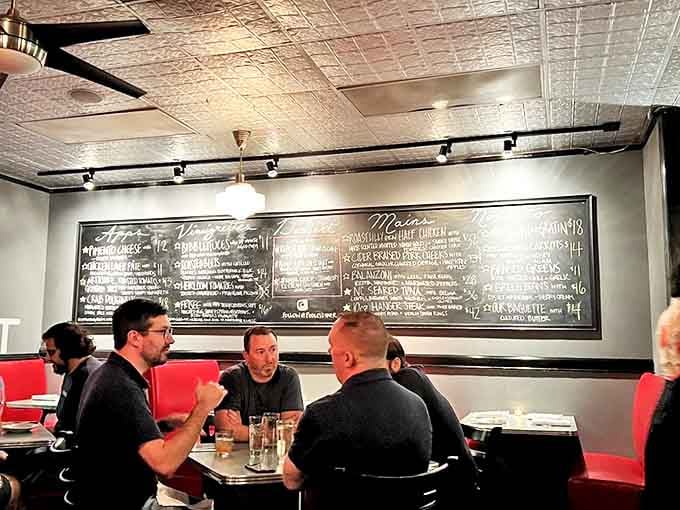 The chalkboard menu and red banquettes create that perfect diner vibe where serious food meets seriously relaxed atmosphere.
