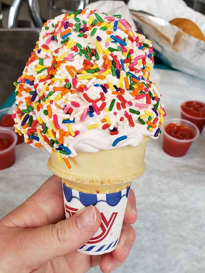 Ice cream piled so high with sprinkles, it looks like a celebration decided to take cone form and never looked back.