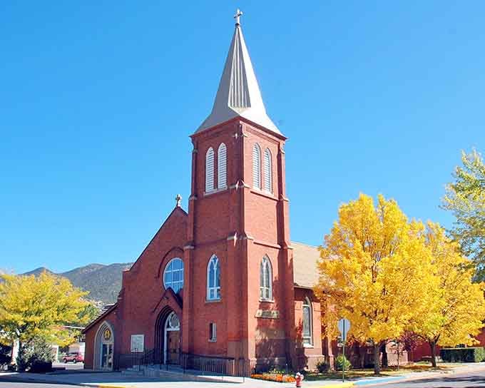 St. Joseph Catholic Church's red brick spire reaches skyward, framed by golden aspens in autumn glory.