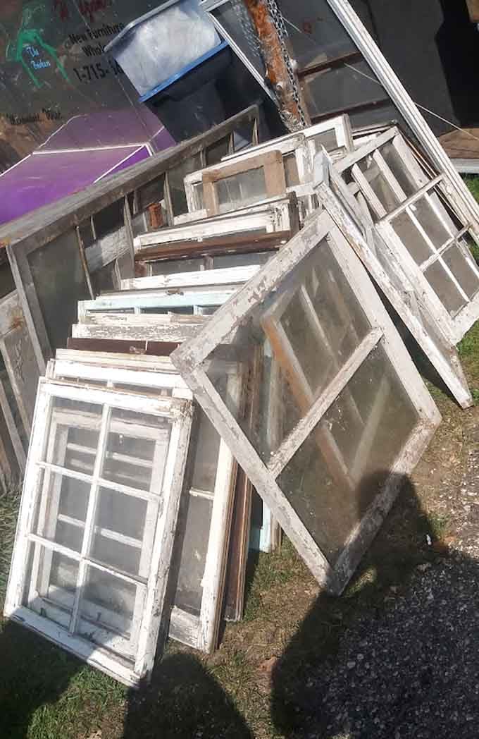 Vintage windows lean against each other like old friends sharing secrets about the homes they once brightened with sunlight.