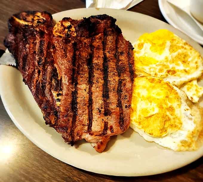 A T-bone steak with grill marks so perfect they could be featured in a geometry textbook, paired with sunny-side-up eggs.