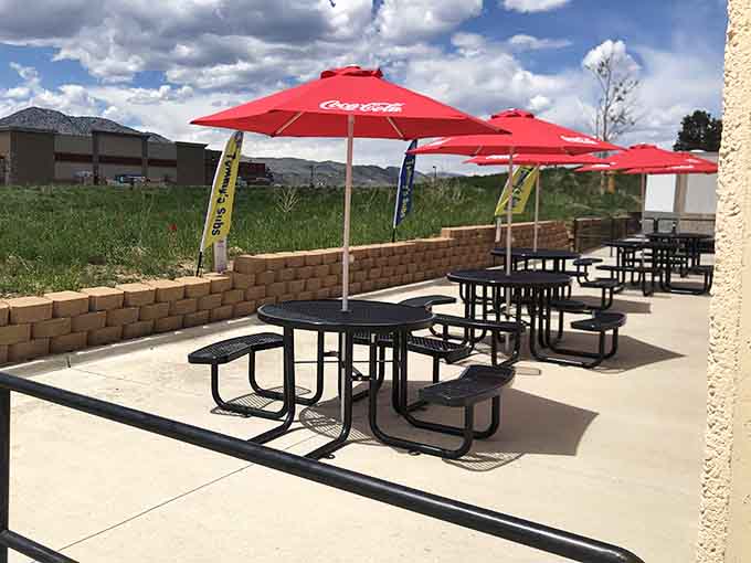 Outdoor seating with mountain views and red umbrellas, because great sandwiches taste even better with Colorado's natural backdrop nearby.