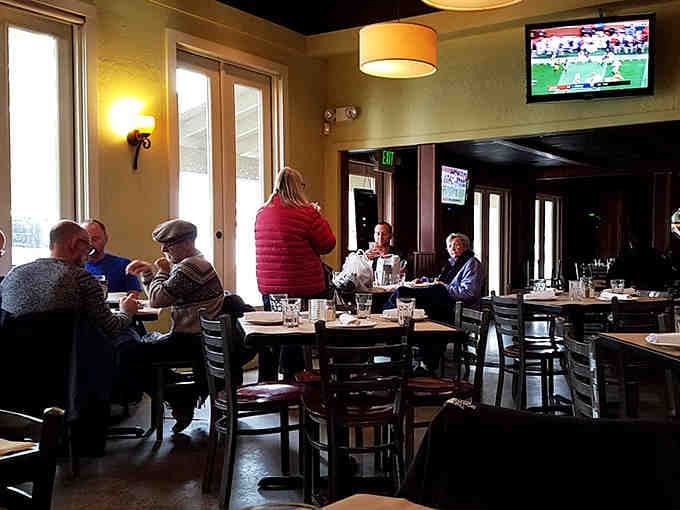 Natural light streaming through windows illuminates diners enjoying their meals in comfortable, unhurried contentment and conversation.