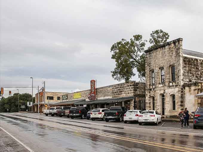 Rain-slicked streets reflect historic limestone buildings, adding romantic atmosphere to this charming Hill Country downtown scene.