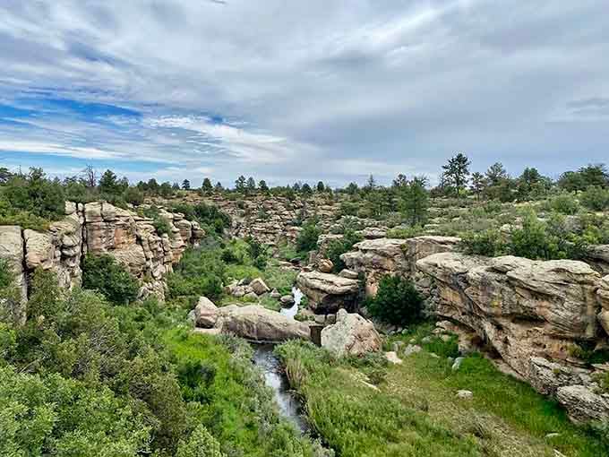 The canyon's layered rock walls drop dramatically to reveal a hidden waterfall tucked between ancient stone formations below.