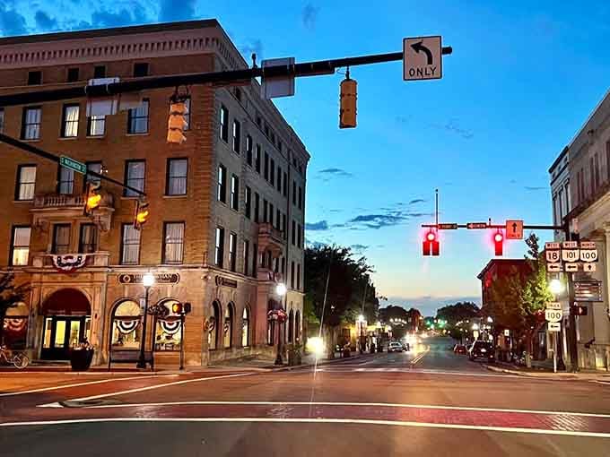 Evening lights glow warmly on historic brick buildings, creating Main Street magic without the big-city price tag.