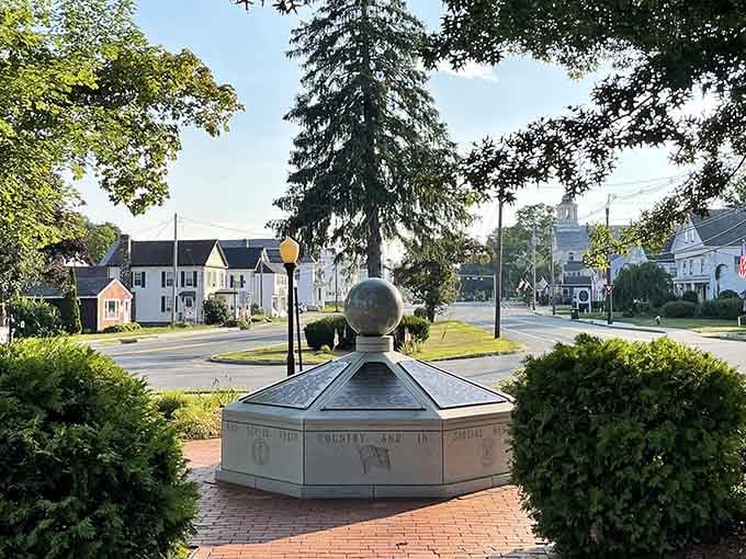 The memorial monument sits peacefully in its brick plaza, honoring those who served while the church steeple watches over everything.