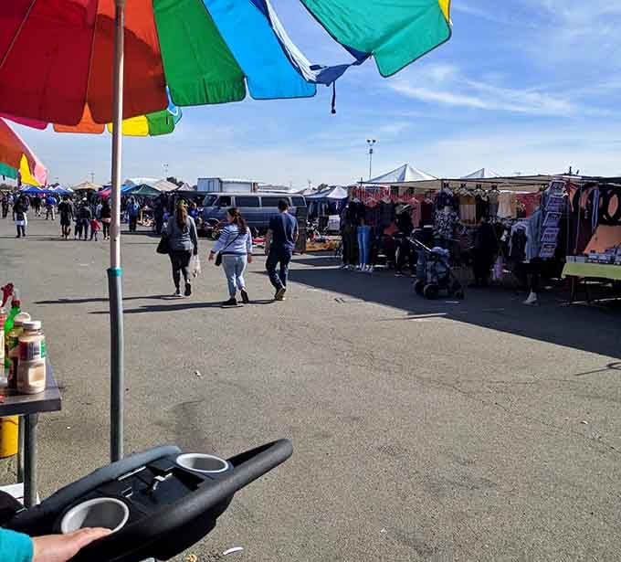 Colorful beach umbrellas provide shade while vendors display their wares in a relaxed, carnival-like atmosphere that invites lingering.