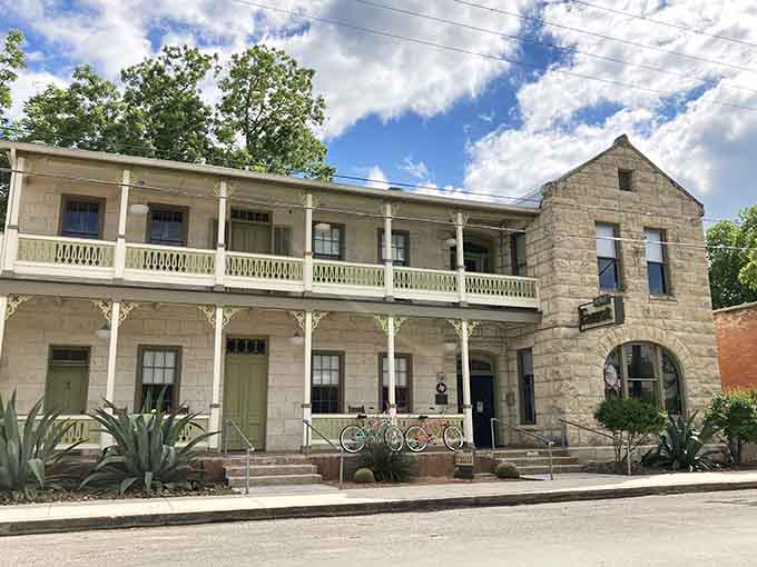 That elegant two-story balcony and limestone walls whisper stories of frontier merchants and their grand ambitions.