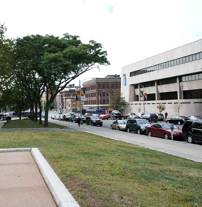 Tree-lined streets provide green breathing room in the urban landscape, where modern buildings meet open spaces for community gathering.