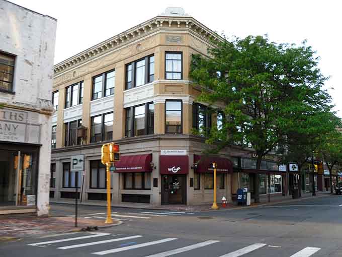 Rounded corner windows and burgundy awnings give this building the kind of character that modern construction just can't fake anymore.