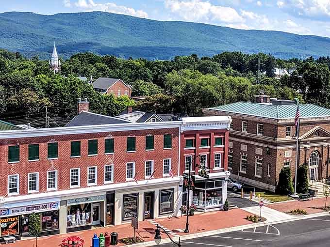 Red brick buildings march down the street in perfect formation, backed by blue mountains that complete this postcard-perfect scene.
