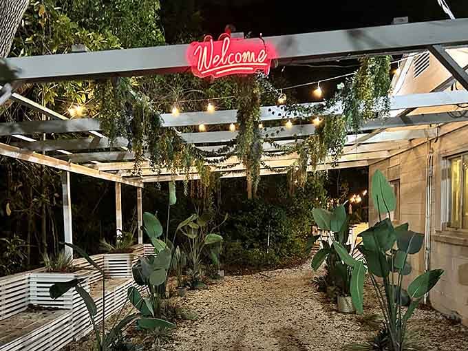 That glowing neon "Welcome" sign isn't just decoration; it's a promise of the tropical escape waiting beyond the greenery.