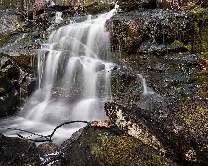 Water cascading over moss-covered rocks like nature's own meditation fountain, minus the subscription fee.