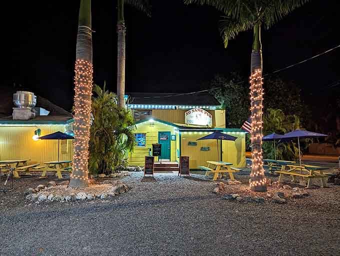The nighttime exterior glows with string lights wrapped around palms, transforming the space into something almost magical and inviting.