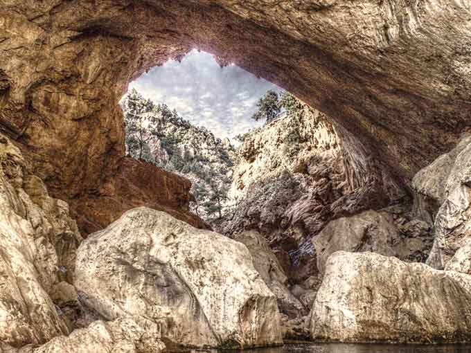 Massive boulders rest beneath the bridge opening, creating a scene that belongs on a Lord of the Rings set.