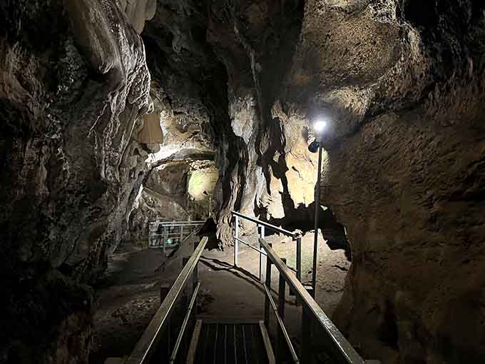 The shadowy figure exploring this limestone cathedral reminds us that some discoveries require a flashlight and courage.