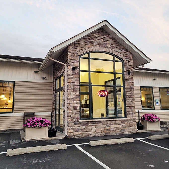 That stone arch window flanked by pink flowers isn't just welcoming, it's practically giving you a hug before you walk in.