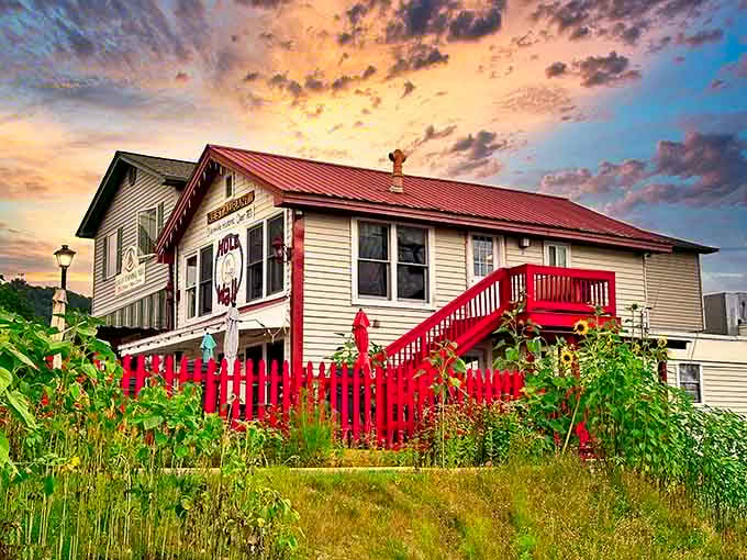 That red metal fence and cream siding aren't just charming, they're practically begging you to come inside for breakfast.