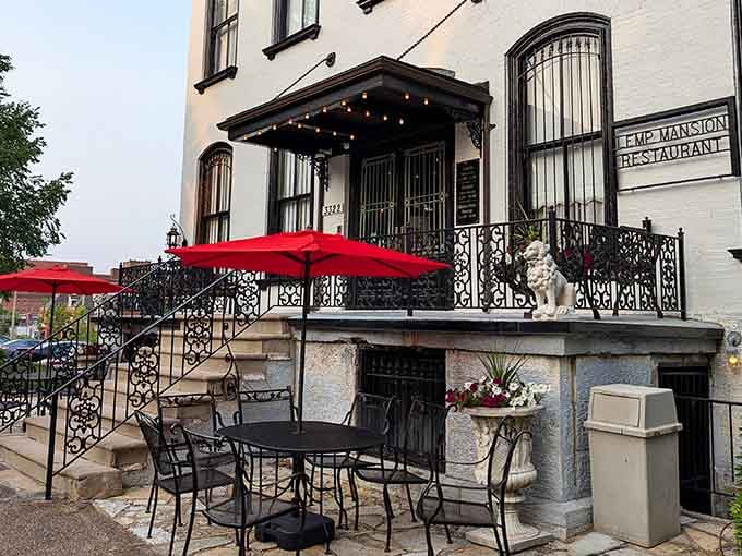 That ornate ironwork patio whispers of genteel afternoons, though the spirits inside prefer their gatherings after dark.