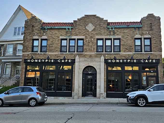 That classic brick facade with red-checkered awning trim whispers "comfort food" louder than your stomach at 9 a.m.
