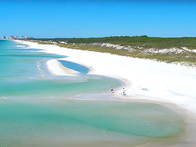 Where emerald waters meet pristine sand and freshwater lakes play hide-and-seek behind towering dunes.