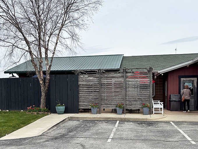 The weathered wood privacy fence and potted flowers create an unexpectedly cozy entrance to your culinary adventure.