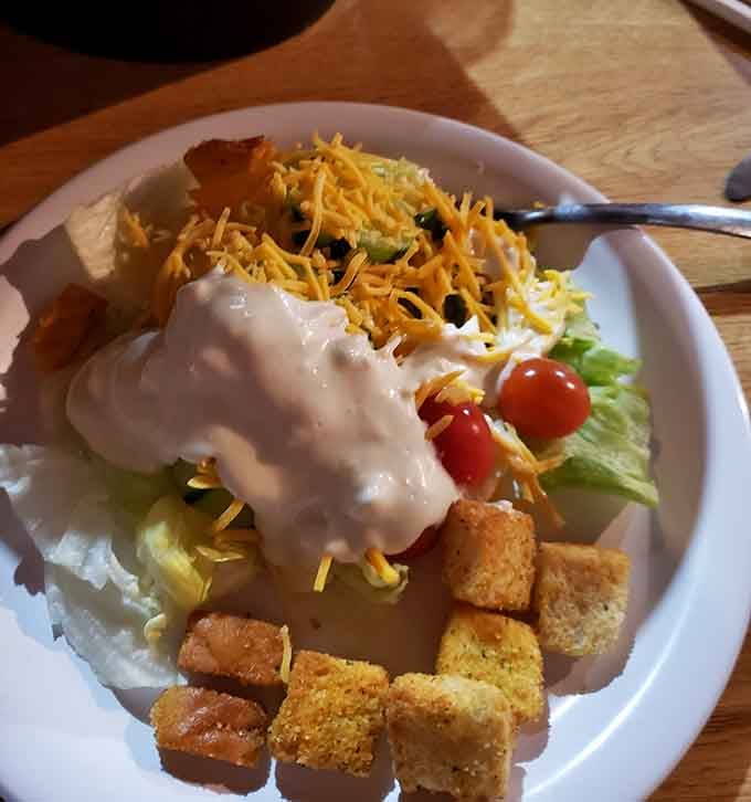 Fresh salad loaded with creamy dressing, shredded cheese, cherry tomatoes, and cornbread croutons balances out all that fried goodness.