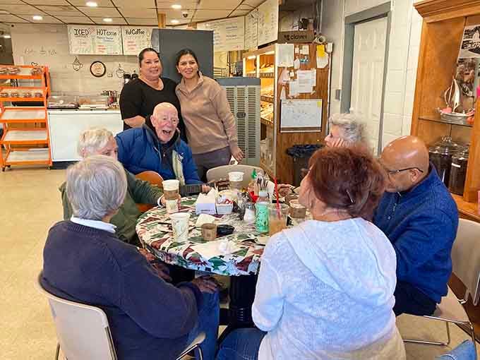Regulars gathering around the table, proving that great donuts create community better than any social media algorithm ever could.