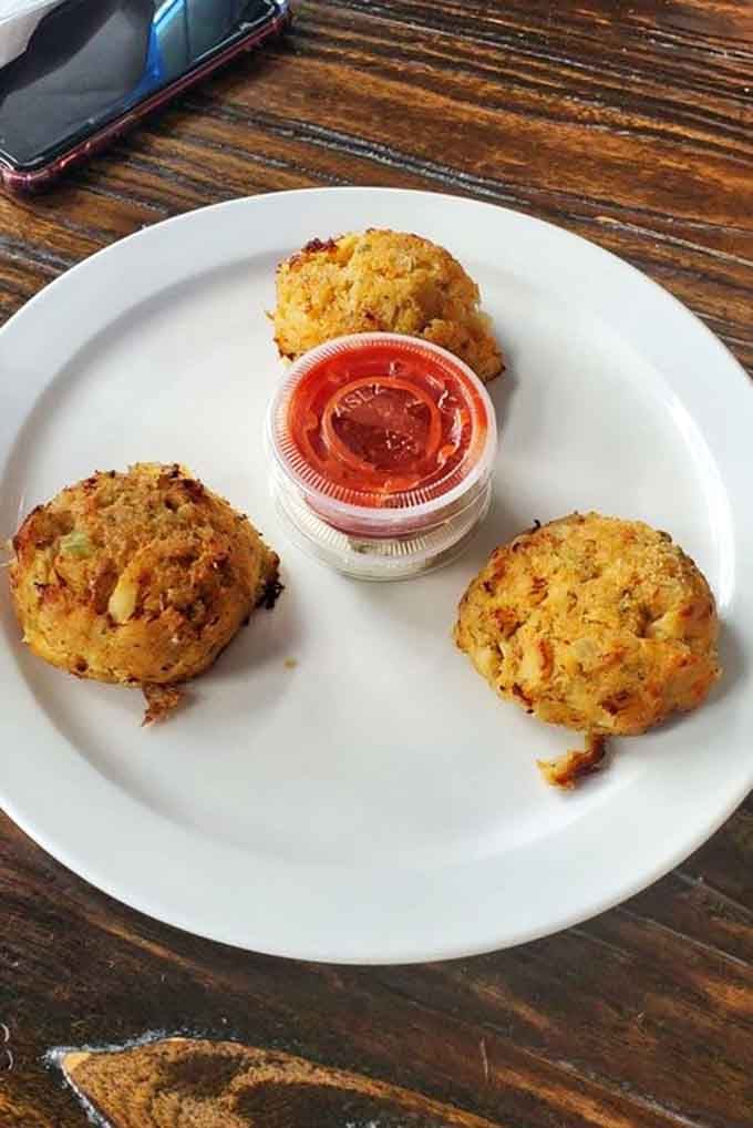 Three perfectly golden clam cakes waiting to be devoured, because one is never enough when they're this good and crispy.